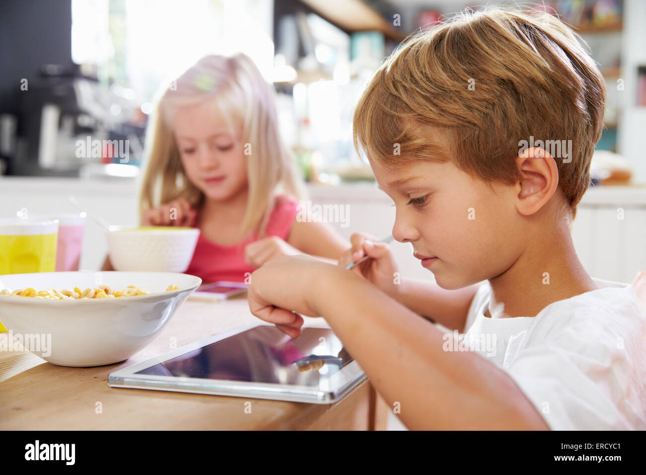 Children Eating Breakfast Whilst Using Digital Tablet Stock Photo - Alamy