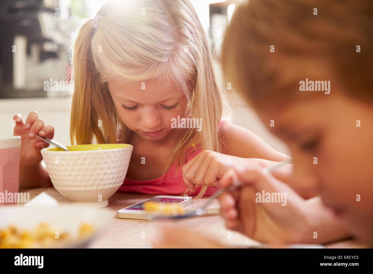 Children Eating Breakfast Whilst Playing With Mobile Phone Stock Photo ...