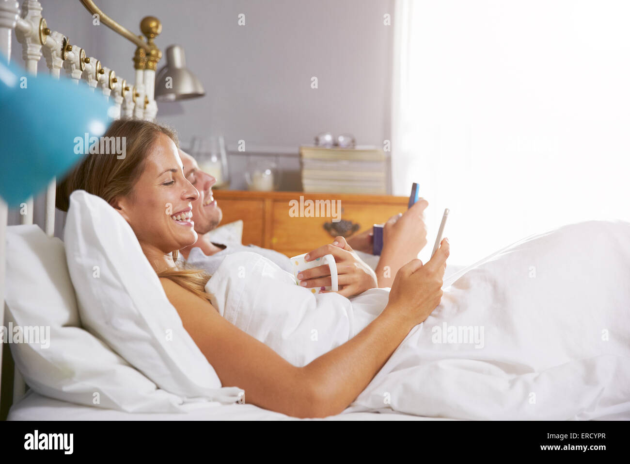 Couple Lying In Bed Checking Mobile Phones Stock Photo - Alamy