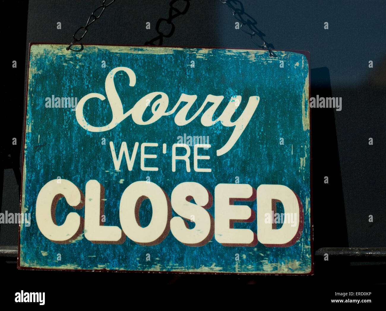A blue textured Sorry we're closed shop sign against a black / dark ...