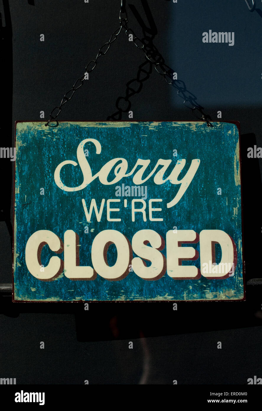 A blue textured Sorry we're closed shop sign against a black / dark ...