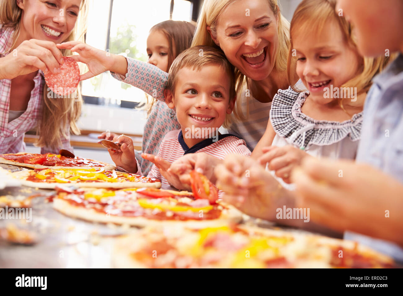 Two women making pizza with kids Stock Photo - Alamy