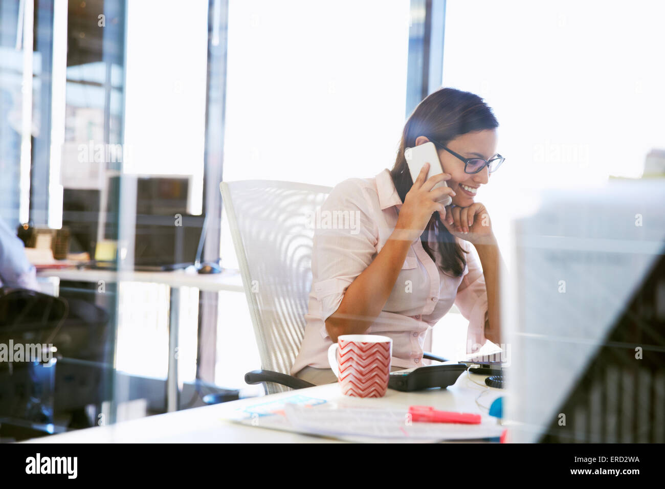 Woman talking using phone at her desk in an office Stock Photo - Alamy