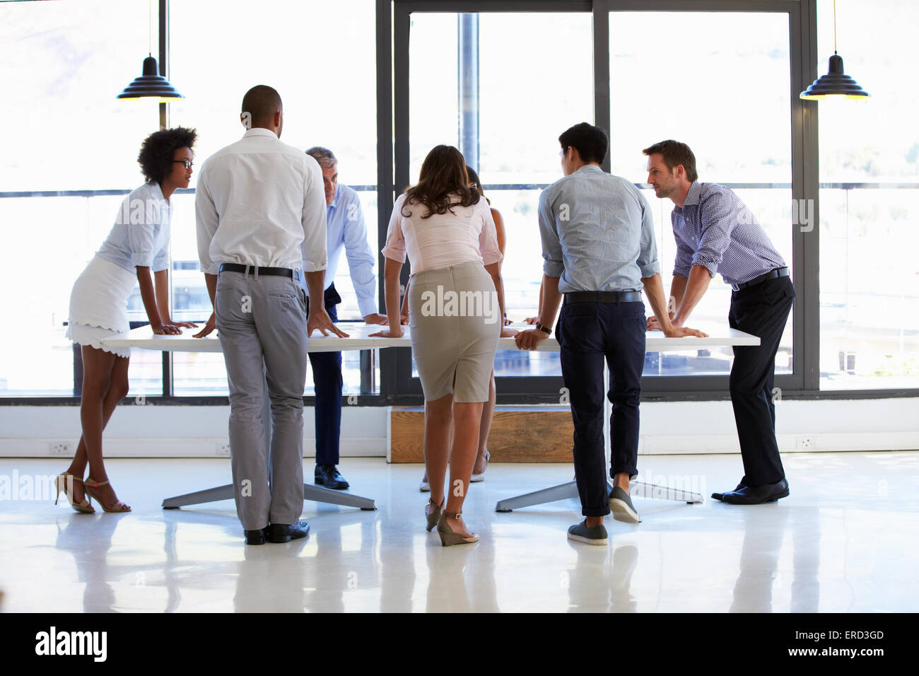 Colleagues standing around a conference table Stock Photo - Alamy
