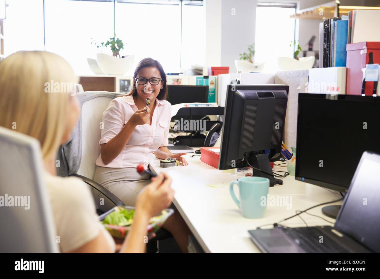 Two women eating lunch at work Stock Photo - Alamy
