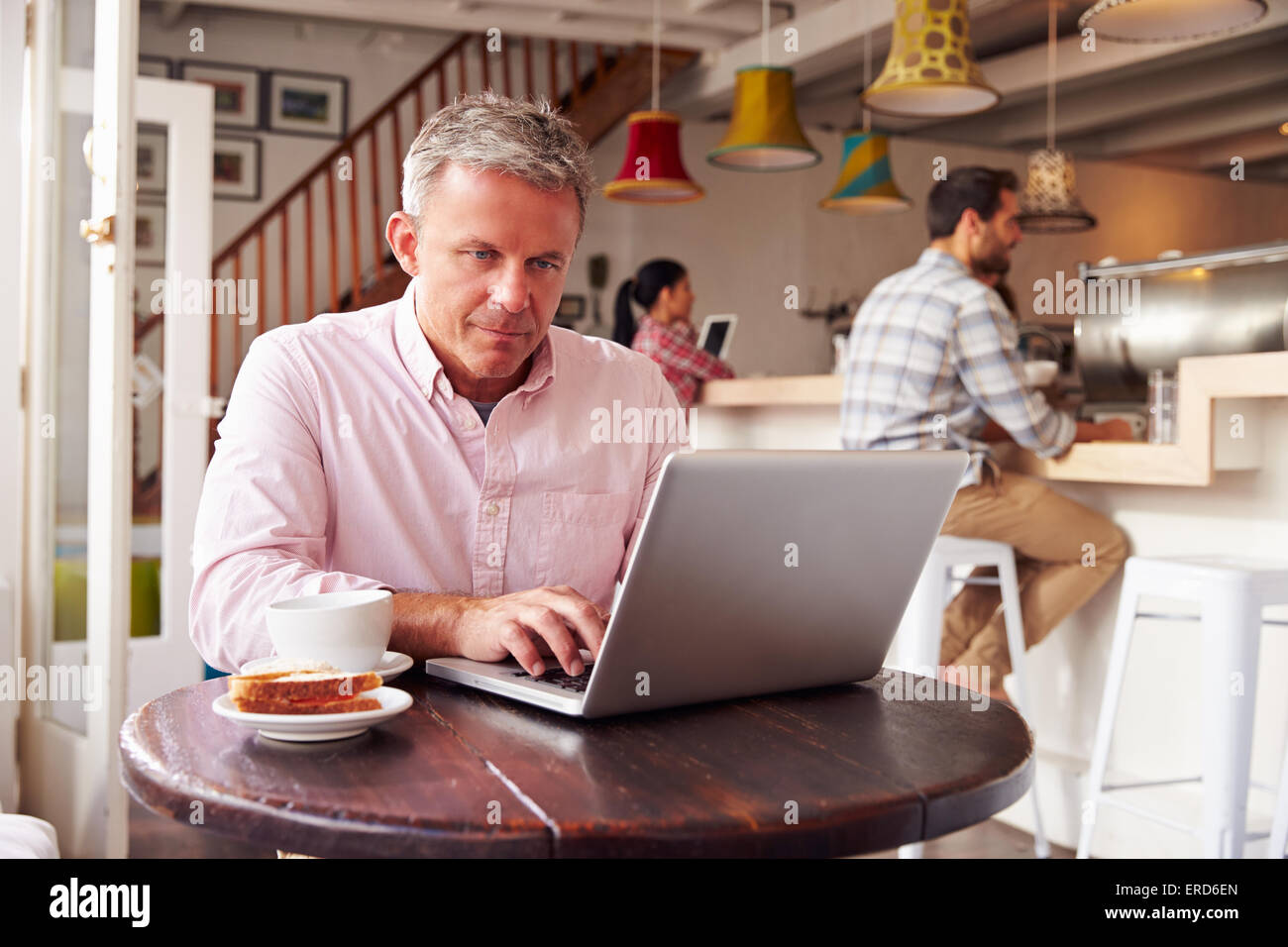 Middle aged man using laptop in a cafe Stock Photo - Alamy