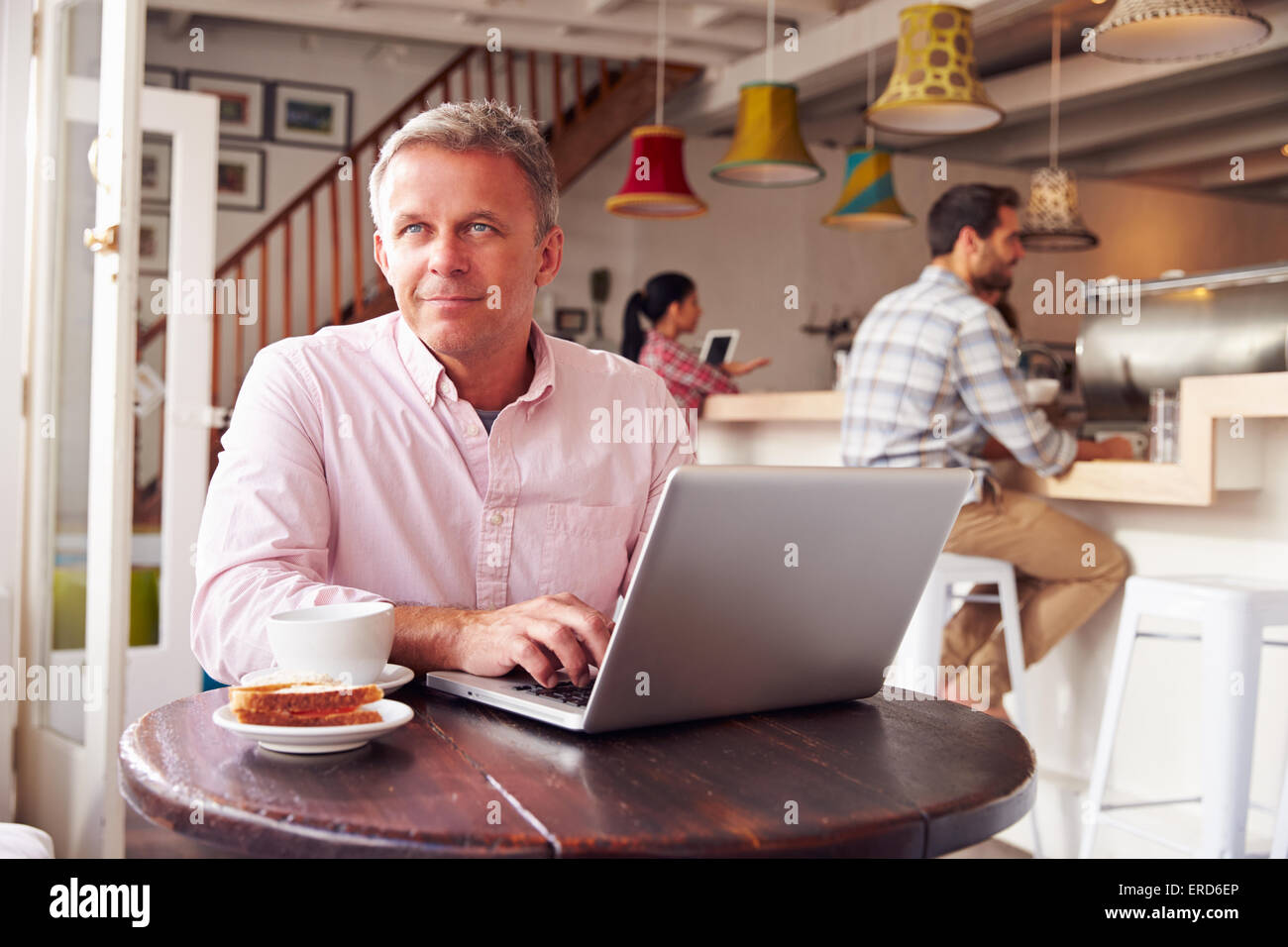 Middle aged man using laptop in a cafe Stock Photo - Alamy
