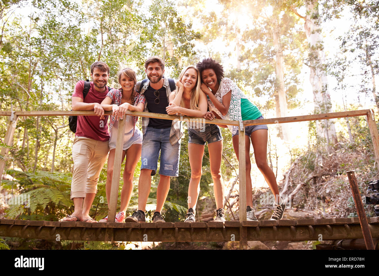 Group Of Friends On Walk Crossing Wooden Bridge In Forest Stock Photo ...