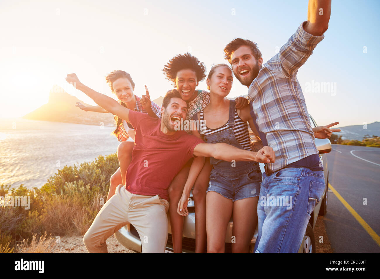 Group Of Friends Standing By Car On Coastal Road At Sunset Stock Photo ...
