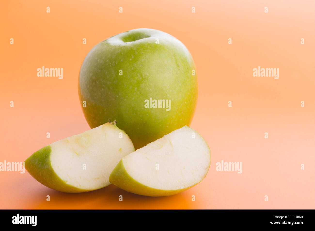 Green apple with slices on gradient orange background Stock Photo - Alamy