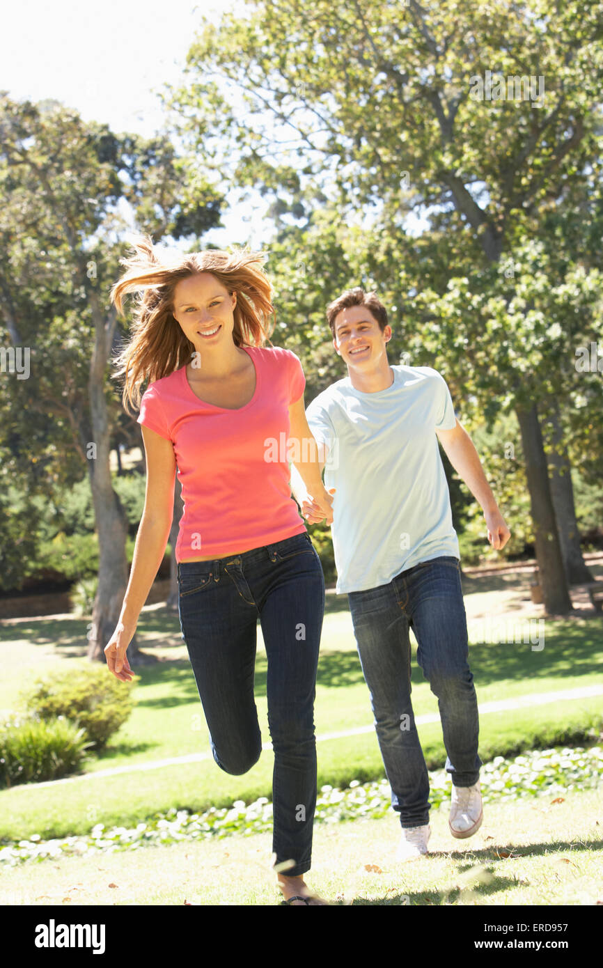 Young Couple Running Through Park Stock Photo - Alamy