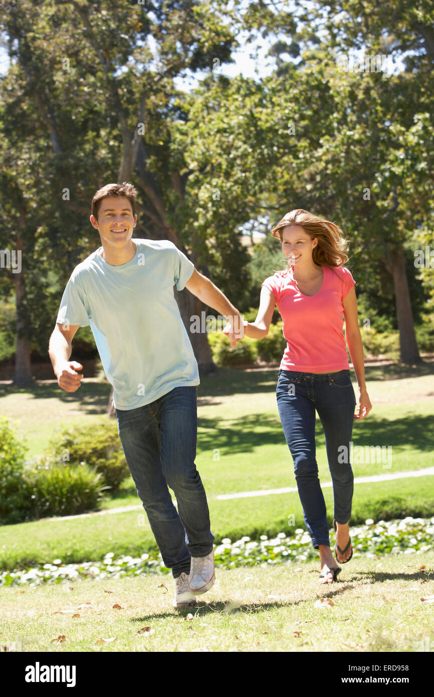 Young Couple Running Through Park Stock Photo - Alamy