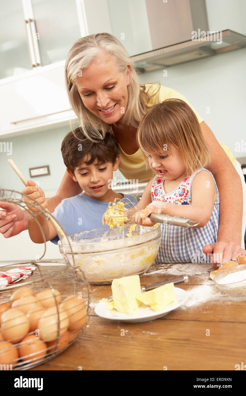 Grandchildren Helping Grandmother To Bake Cakes In Kitchen Stock Photo ...
