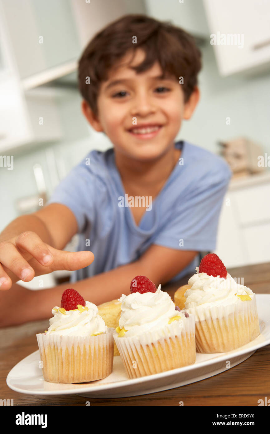 Young Boy Eating Cakes In Kitchen Stock Photo - Alamy