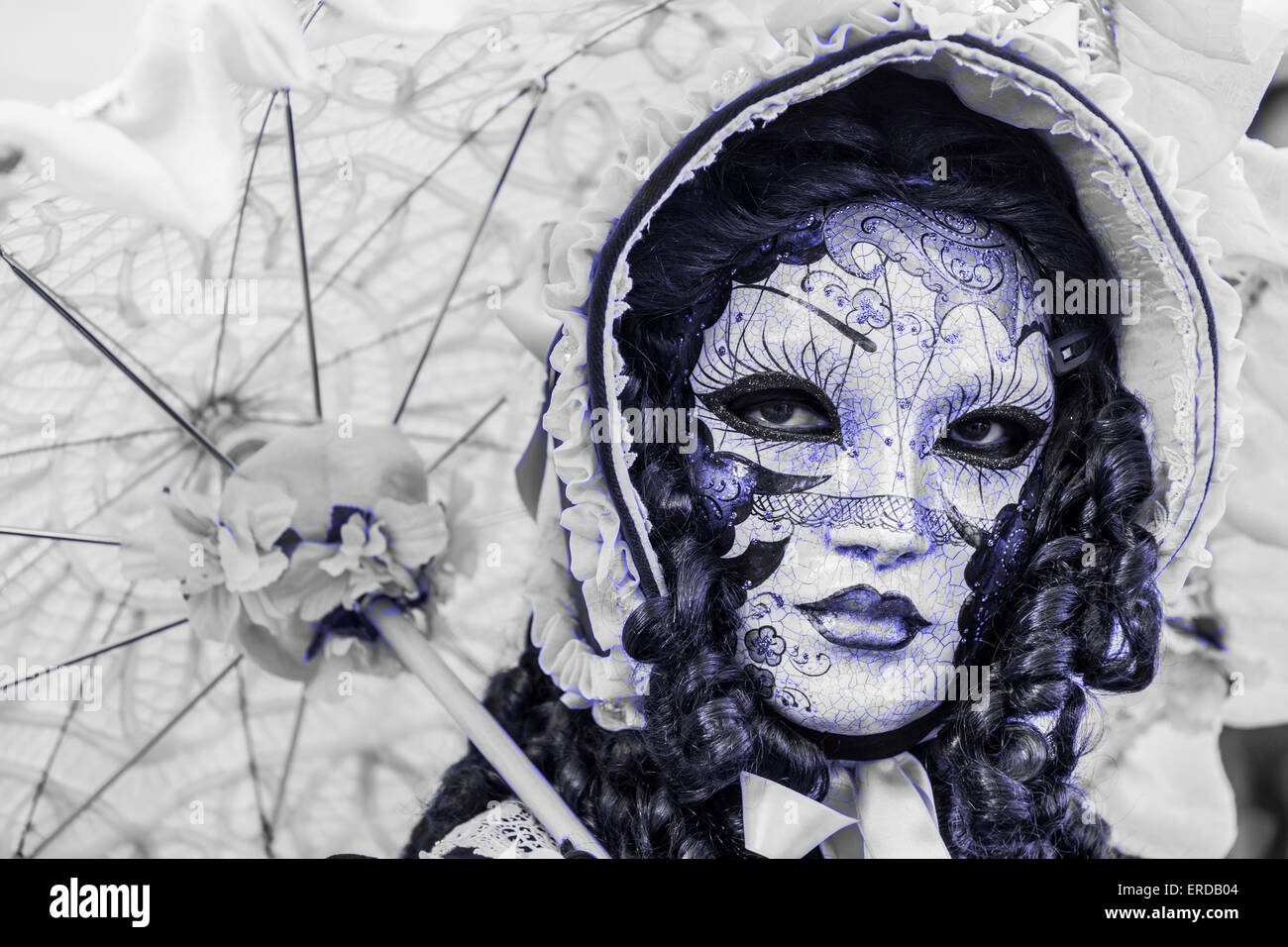 Greyscale closeup with violet highlights of woman in mask with parasol ...