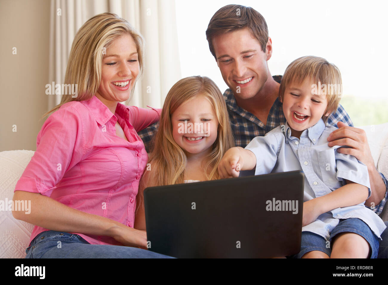 Family Using Laptop On Sofa At Home Stock Photo - Alamy