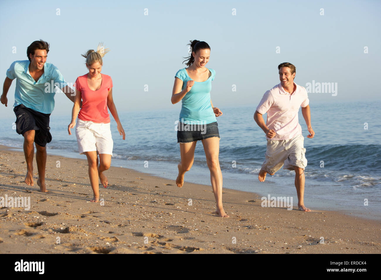 Group Of Friends Running Along Beach Stock Photo - Alamy