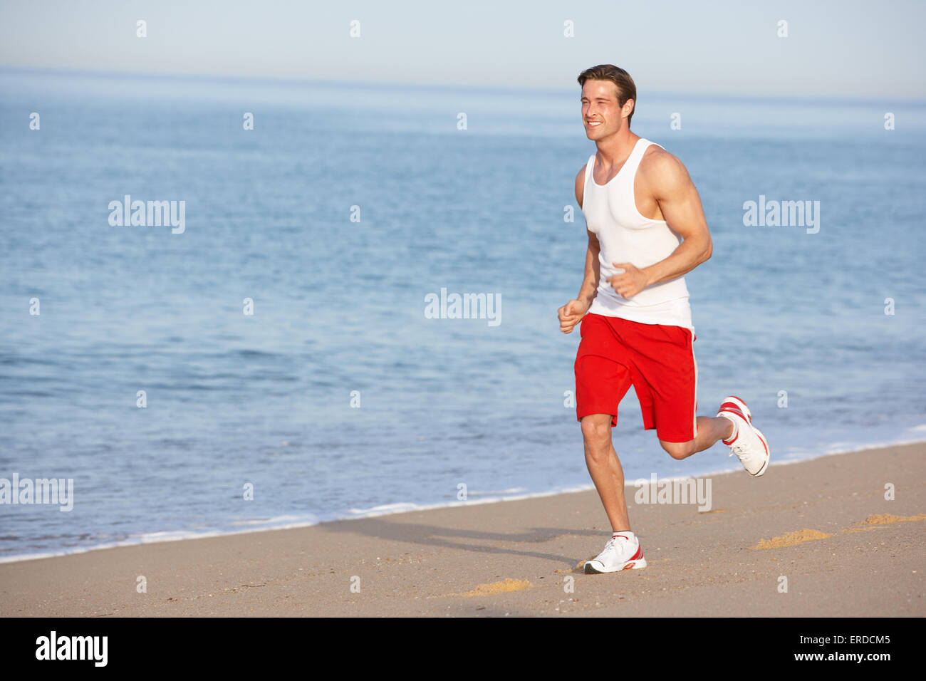 Young Man Jogging Along Beach Stock Photo - Alamy