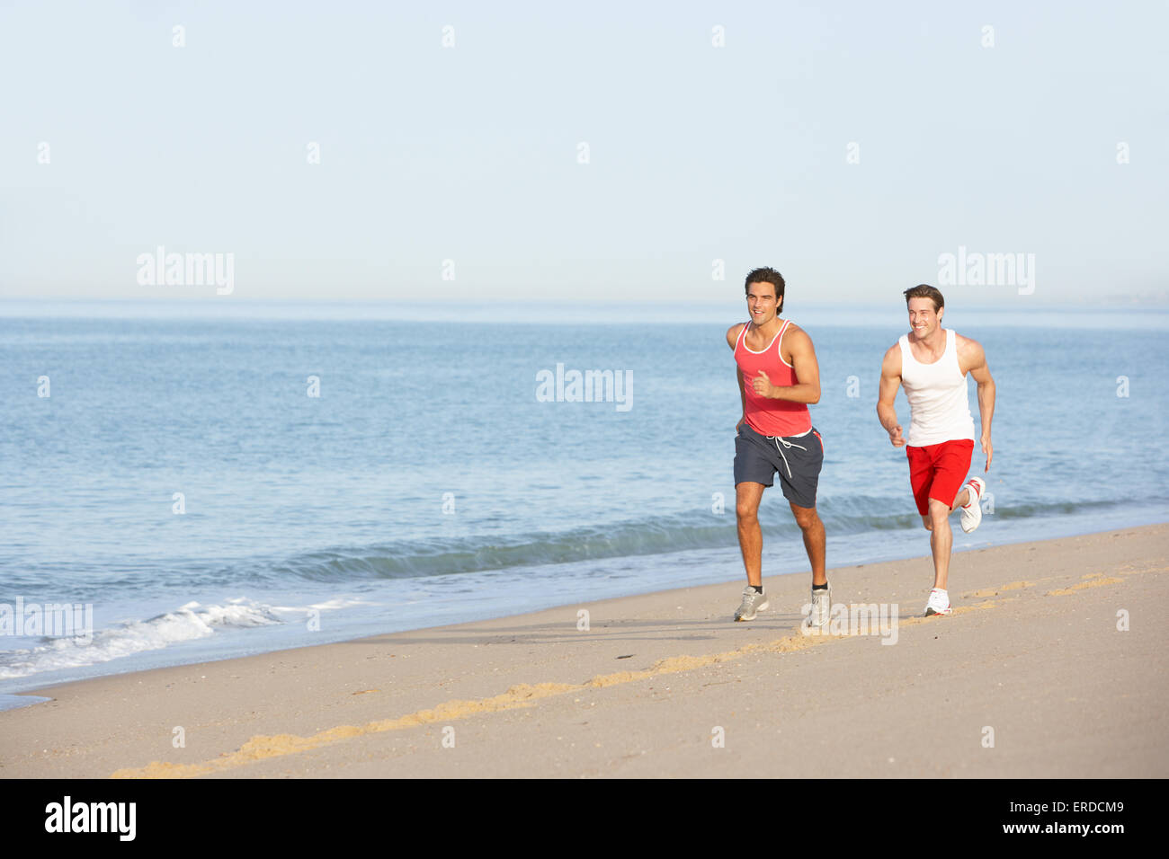 Two Young Men Jogging Along Beach Stock Photo - Alamy