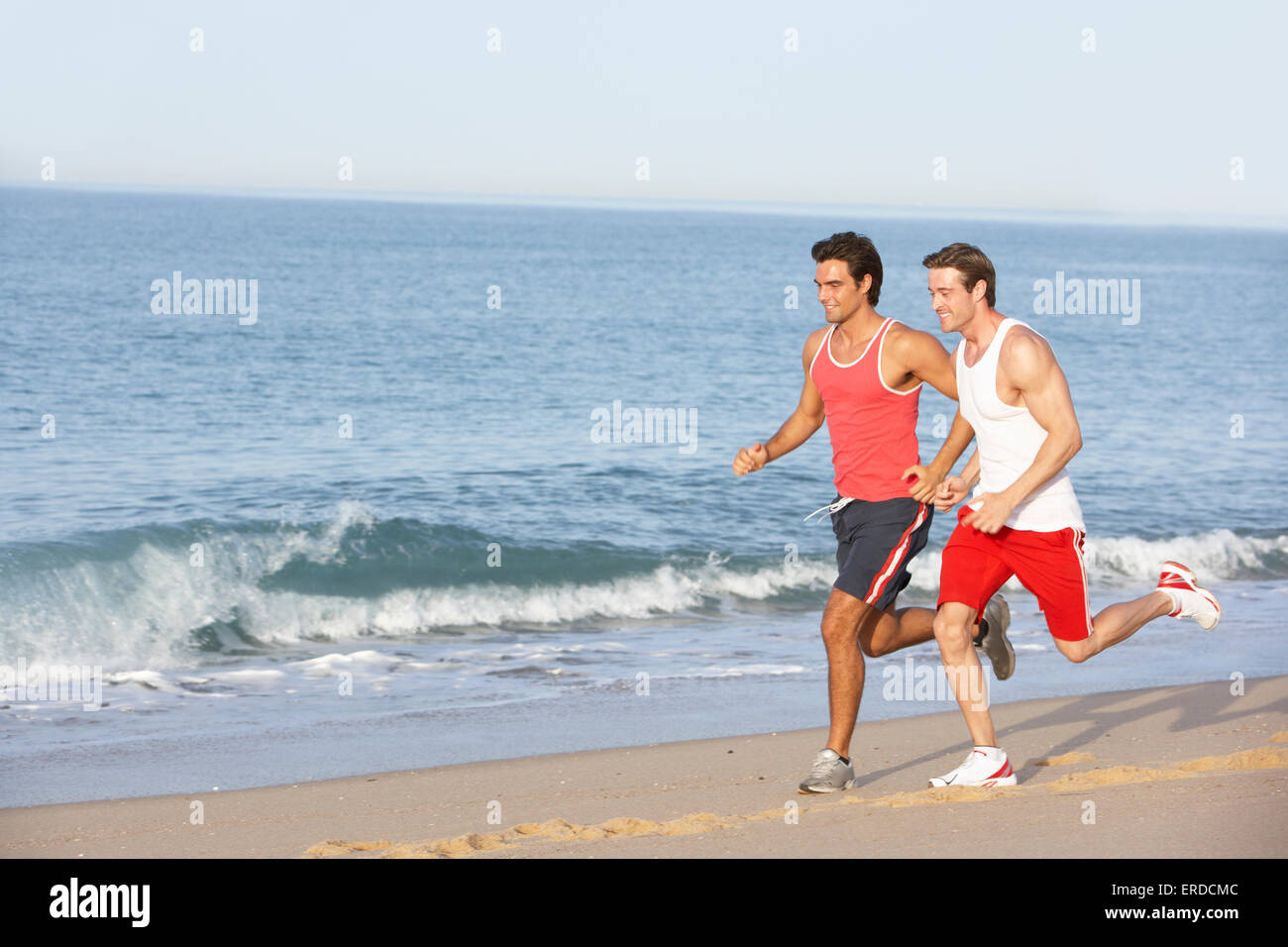 Two Young Men Jogging Along Beach Stock Photo - Alamy