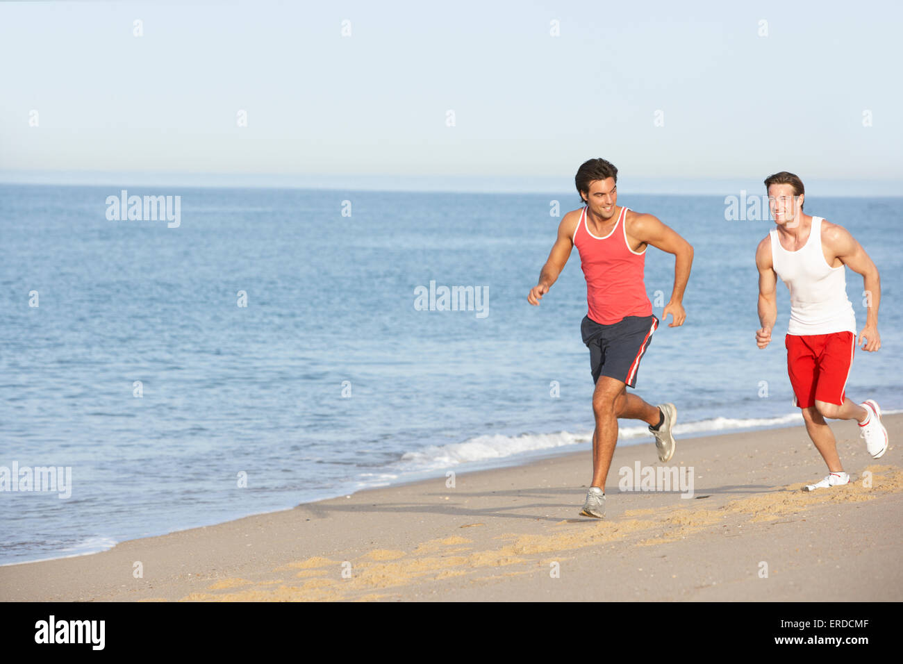 Two Young Men Jogging Along Beach Stock Photo - Alamy