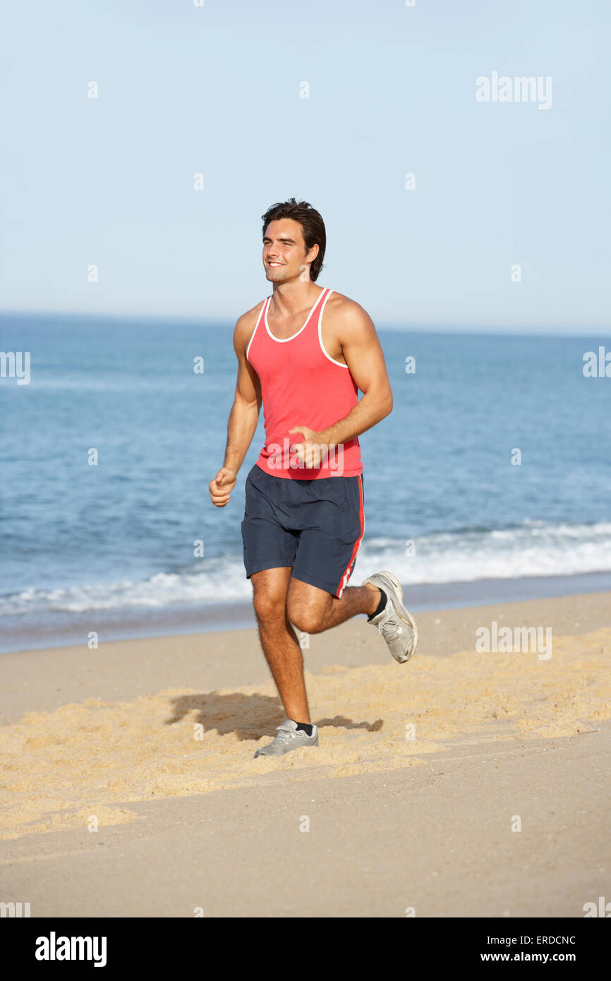 Young Man Jogging Along Beach Stock Photo - Alamy