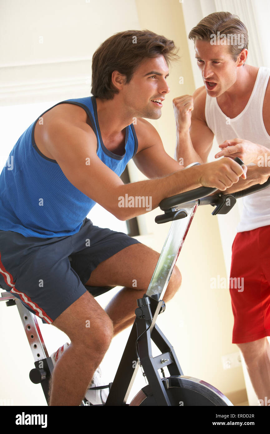 Young Man On Exercise Bike With Trainer Stock Photo - Alamy