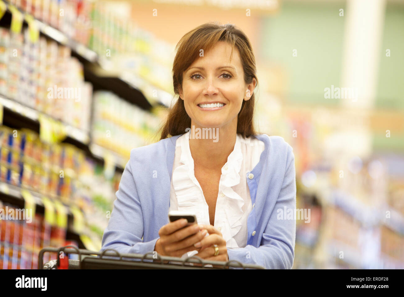 Woman using cellphone in supermarket Stock Photo - Alamy