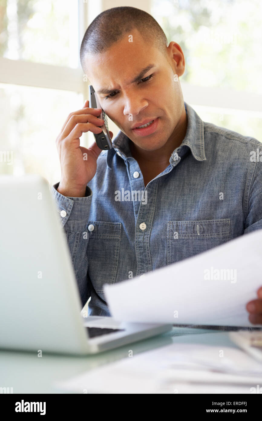 Frustrated Young Man On Phone Using Laptop At Home Stock Photo - Alamy