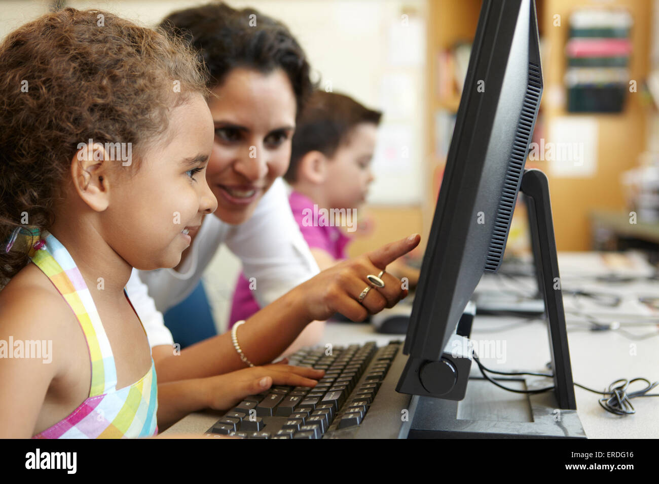 Elementary School Pupil With Teacher In Computer Class Stock Photo - Alamy