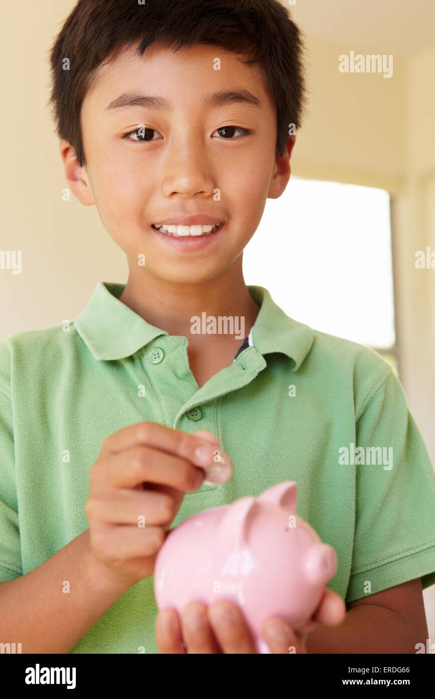 Young boy putting money in piggybank Stock Photo - Alamy