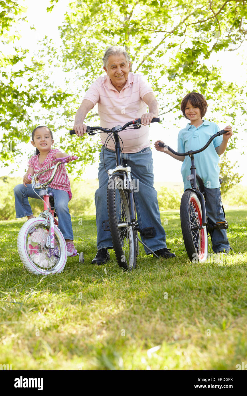 Hispanic Grandfather With Grandchildren In Park Riding Bikes Stock ...