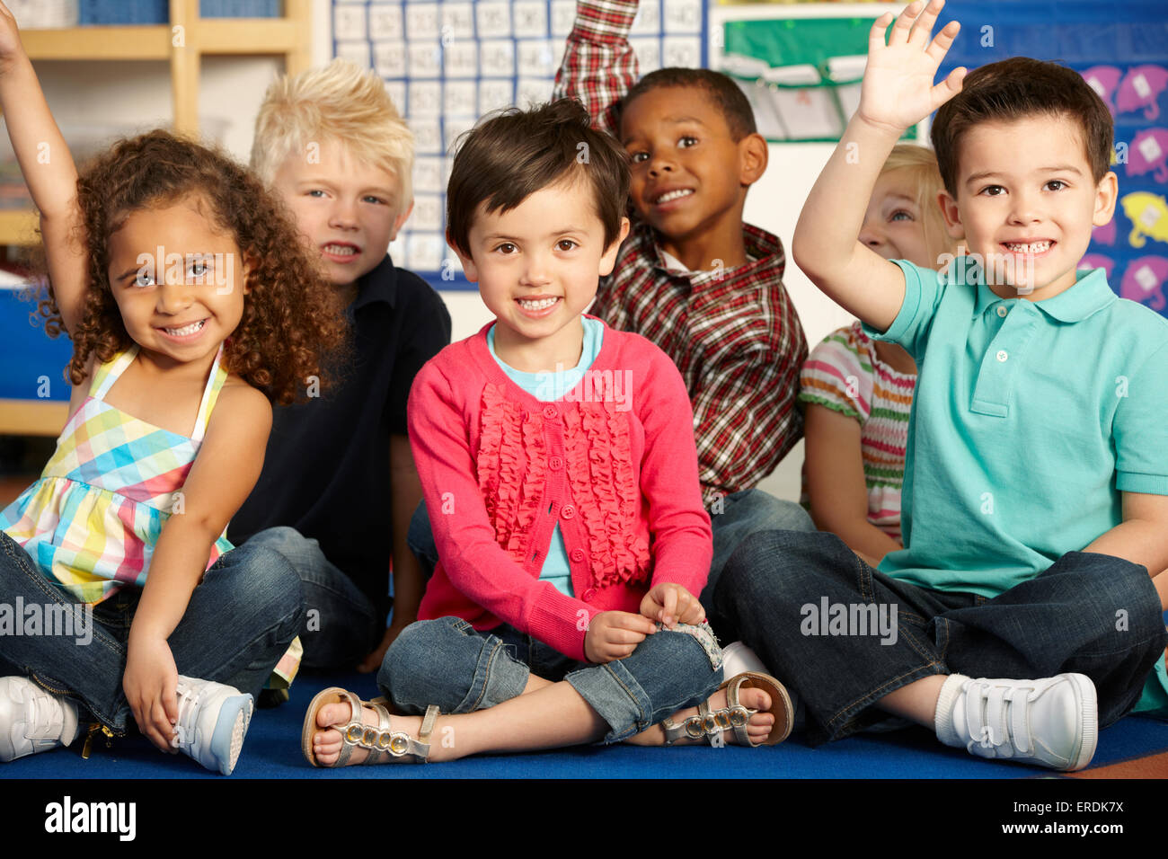 Group Of Elementary Age Schoolchildren Answering Question In Class ...