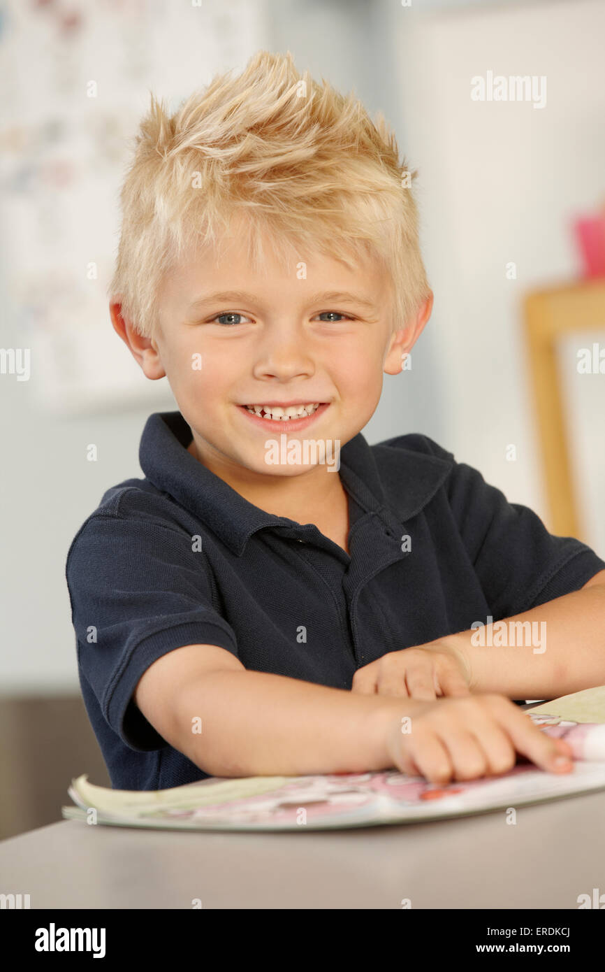 Elementary Age Schoolboy Reading Book In Class Stock Photo - Alamy