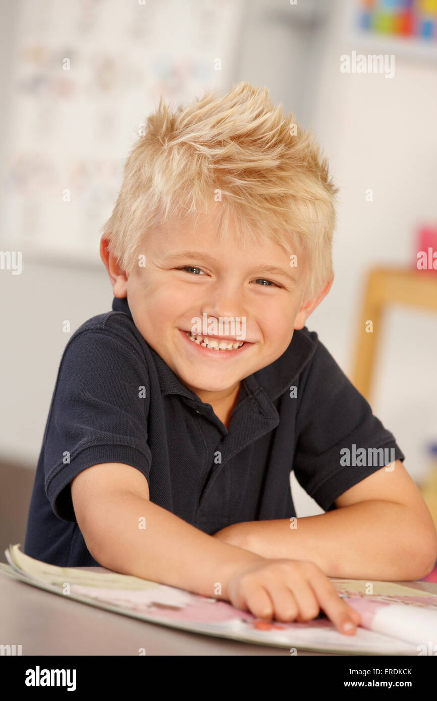 Elementary Age Schoolboy Reading Book In Class Stock Photo - Alamy