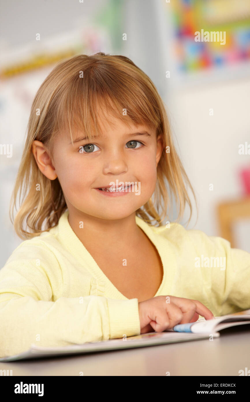 Elementary Age Schoolgirl Reading Book In Class Stock Photo - Alamy