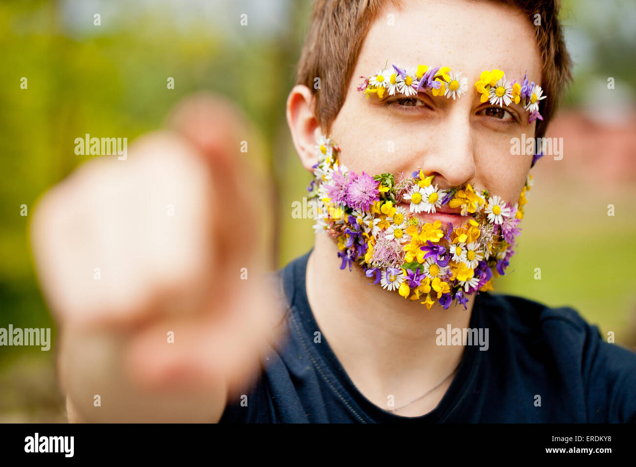 young hipster man with flowers instead of his face hair pointing out ...