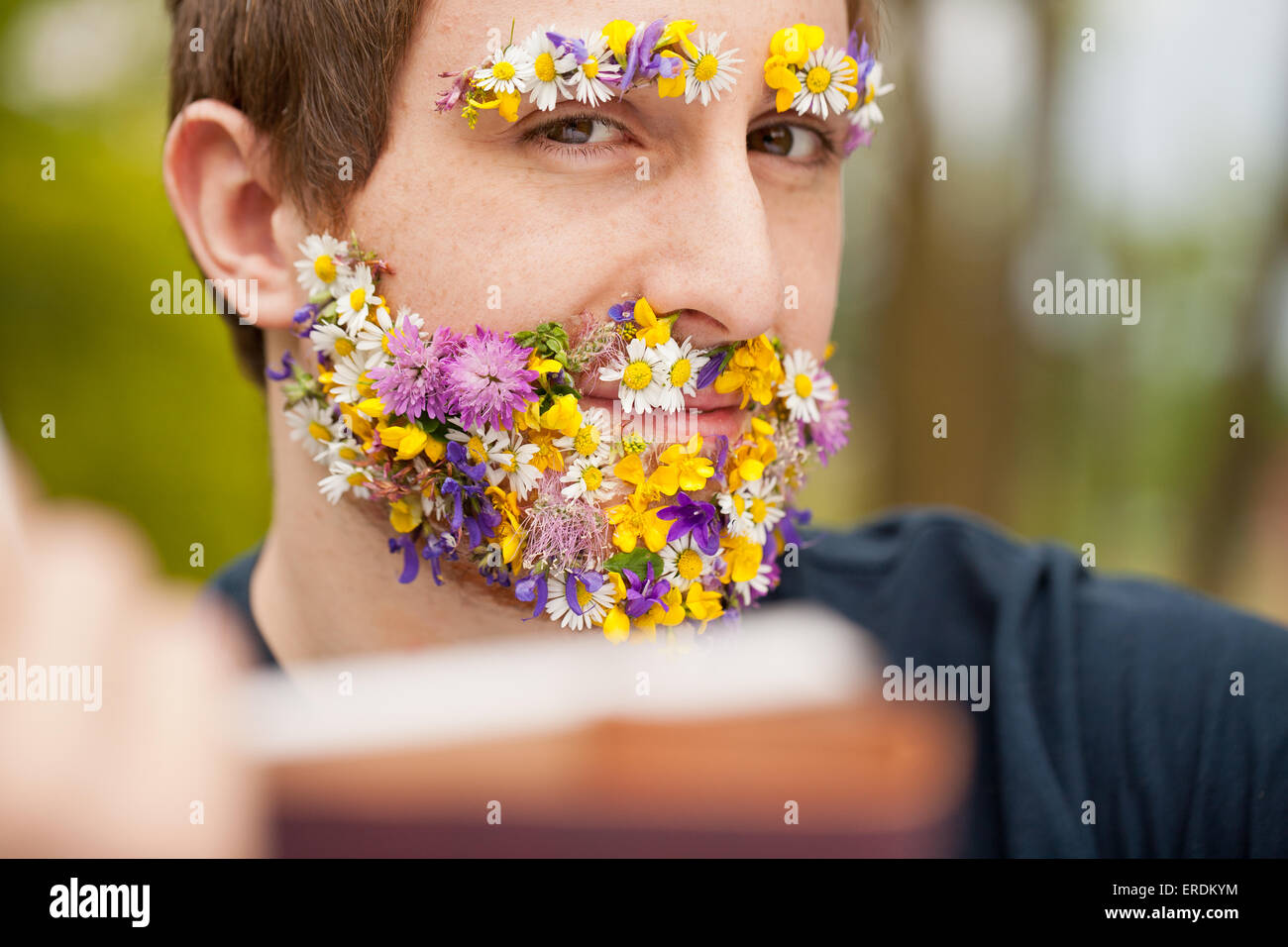 young man with his face flower-covered on his beard and eyebrows ...