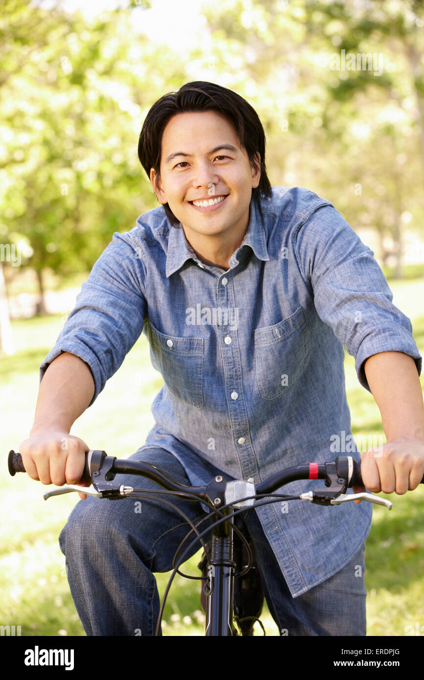 Asian man riding bike in park Stock Photo - Alamy