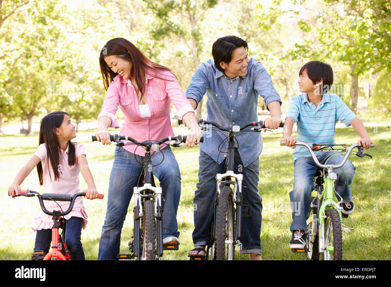Asian family riding bikes in park Stock Photo - Alamy