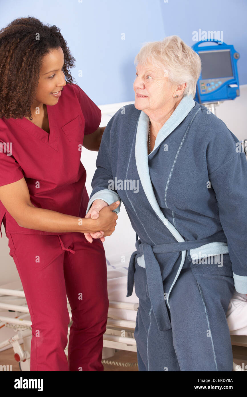 Nurse helping senior woman out of bed in hospital Stock Photo - Alamy