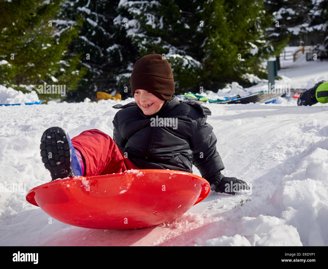 Caucasian boy sledding on snowy hill Stock Photo - Alamy
