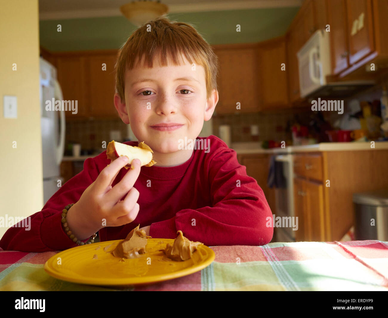 Caucasian boy eating apple with peanut butter snack Stock Photo - Alamy