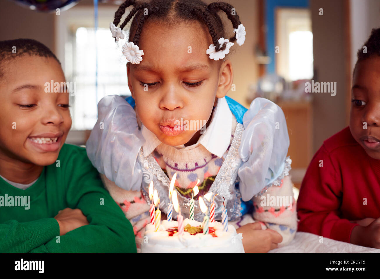 Three boys blowing out the candle on a birthday cake hi-res stock ...