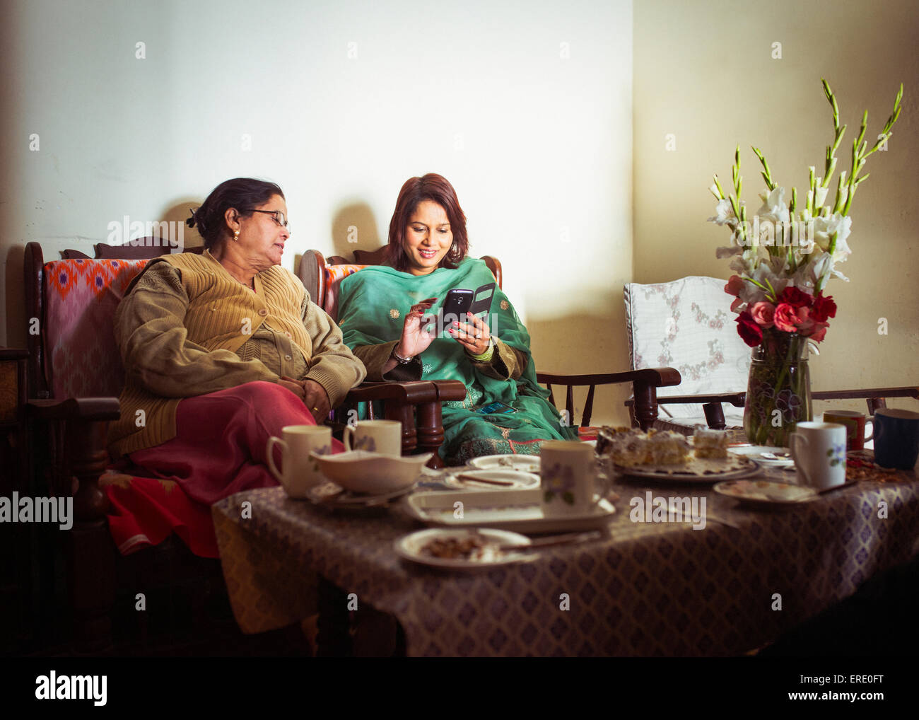Mother and daughter using cell phone at dinner table Stock Photo - Alamy