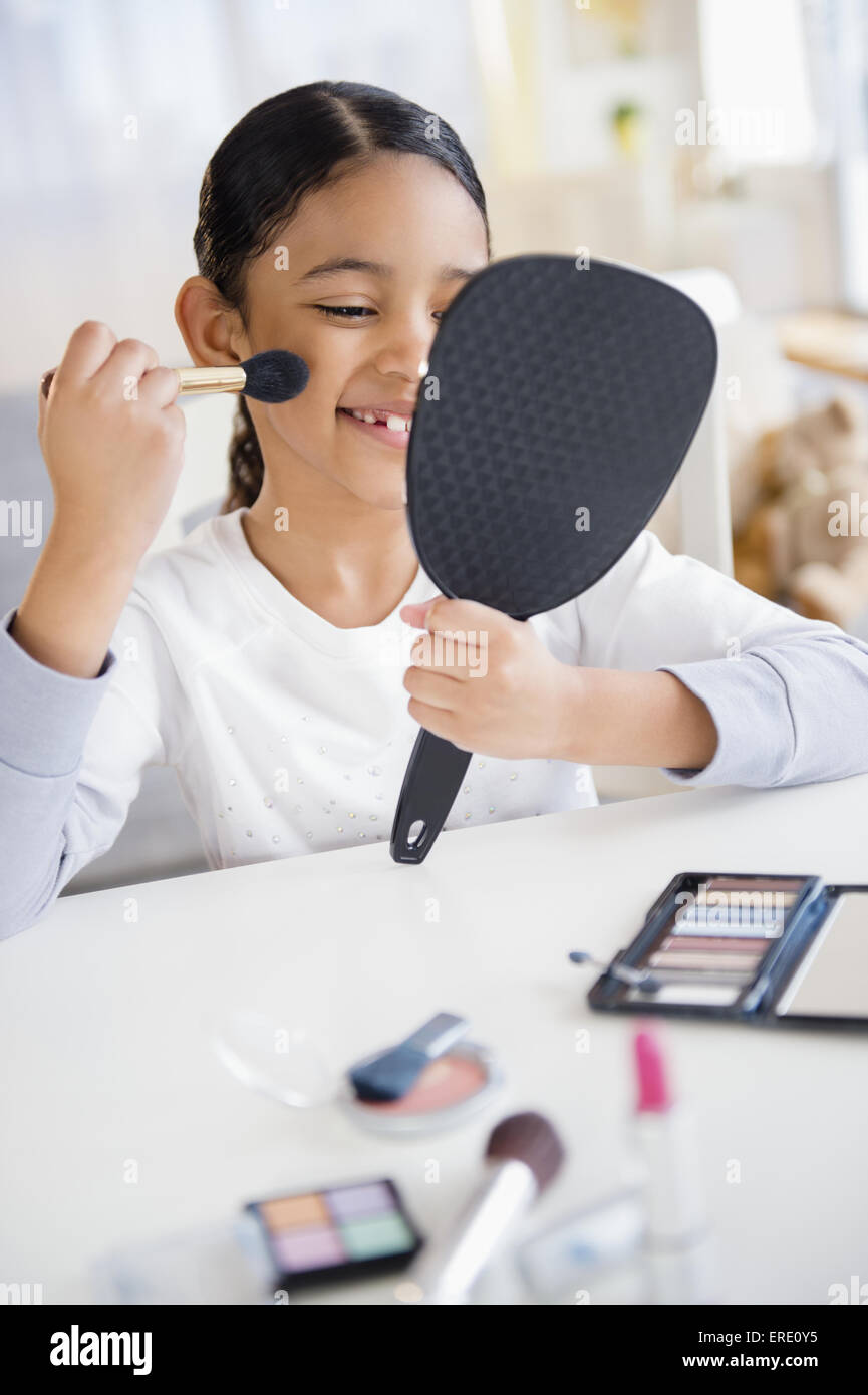 Mixed race girl applying makeup with brush Stock Photo - Alamy