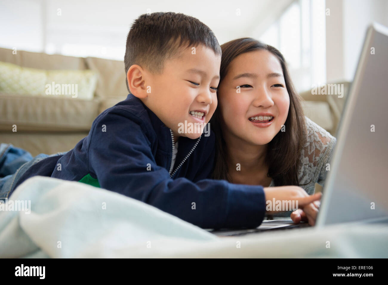Asian brother and sister using laptop on living room floor Stock Photo ...