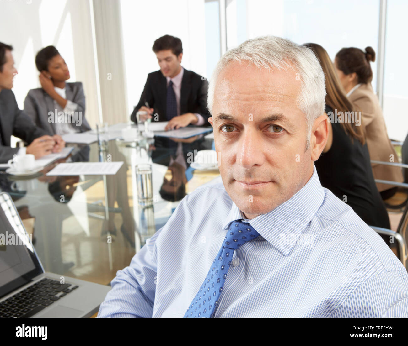 Businessman Sitting Around Boardroom Table With Colleagues Stock Photo ...