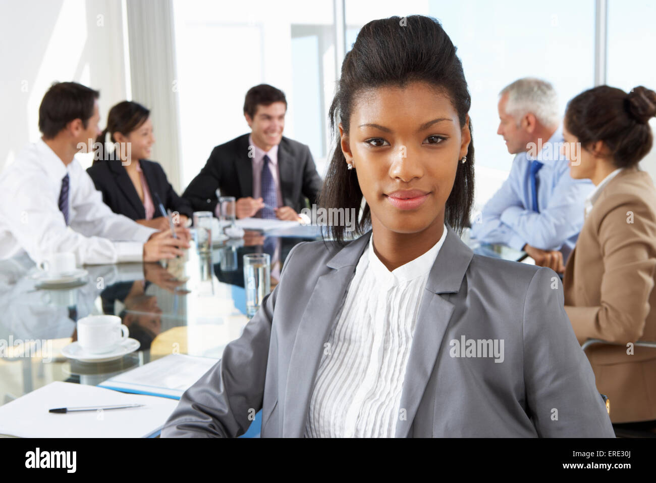 Businesswoman Sitting Around Boardroom Table With Colleagues Stock ...