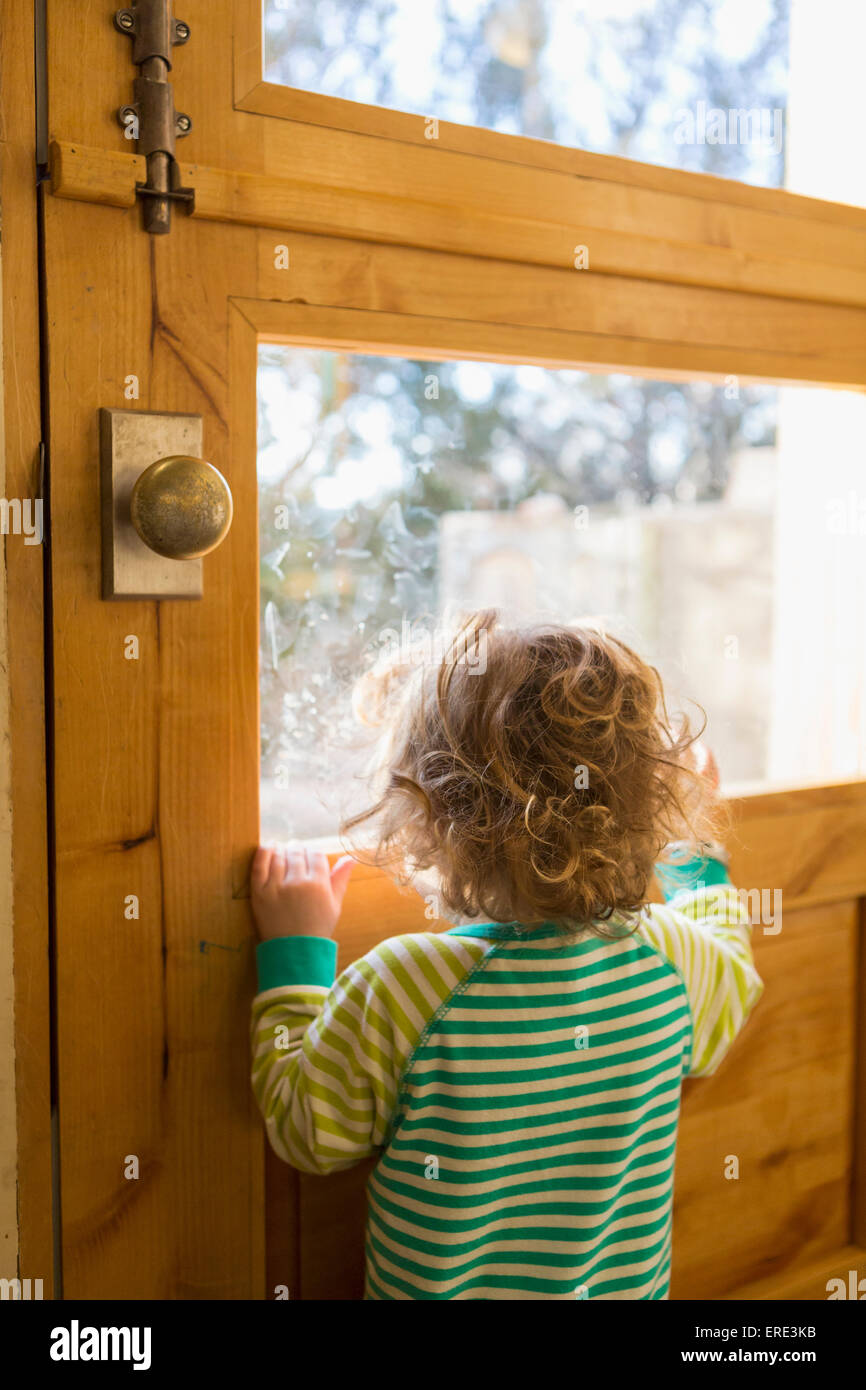 Caucasian boy looking out door window Stock Photo - Alamy